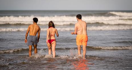 Group walking into the water enjoying the Mussenden Unwind experience