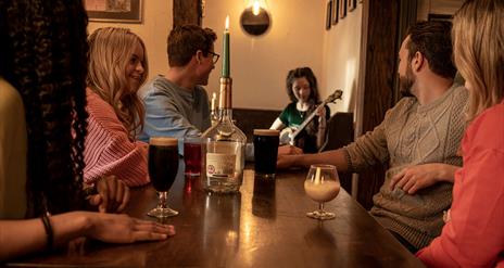 Group watching the musician play live traditional music as part of the Ceili & Craic experience at The Ponderosa. 