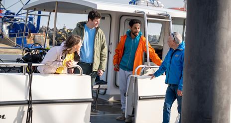 The guide/skipper of the boat welcoming guests onto the boat as part of the Giant Shipwrecks of the North Coast experience