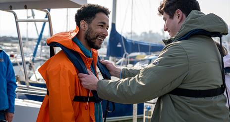 Two men fixing their lifejackets as part of the Giant Shipwrecks of the North Coast experience