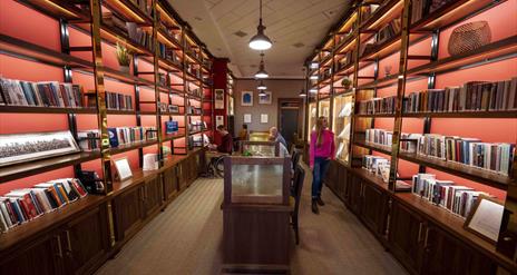 A group explores a beautiful red room with shelves filled with memorabilia relating to Seamus Heaney