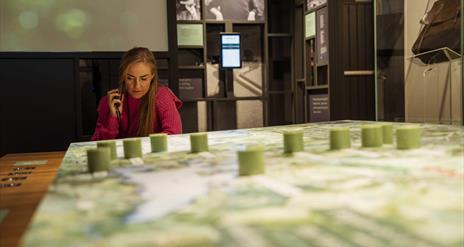 A lady listens to an audio device whilst looking at a display at Seamus Heaney HomePlace
