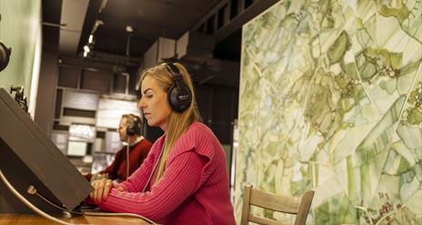 A lady listens to an interactive display at the Heaney Homeplace