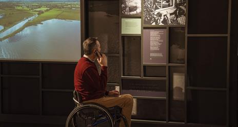 A man in a wheelchair listens to an audio tour of the Seamus Heaney HomePlace